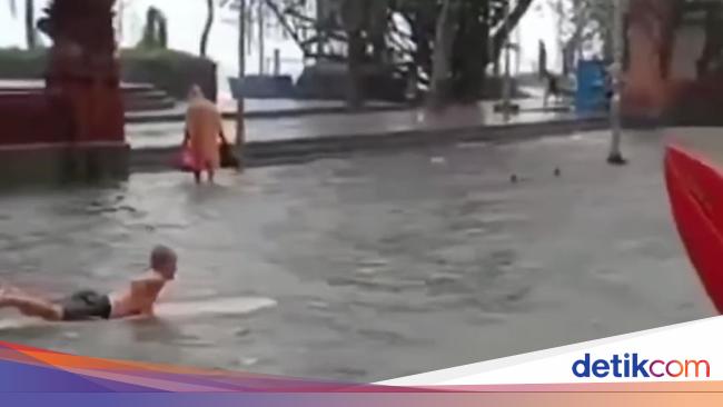 Aksi Bule Main Papan Surfing Saat Banjir di Jalan Pantai Kuta