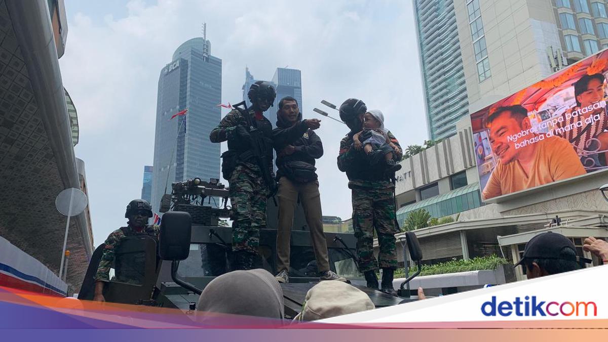 Warga Berfoto di Atas Tank TNI Saat Pawai Alutsista Melintas di Bundaran HI